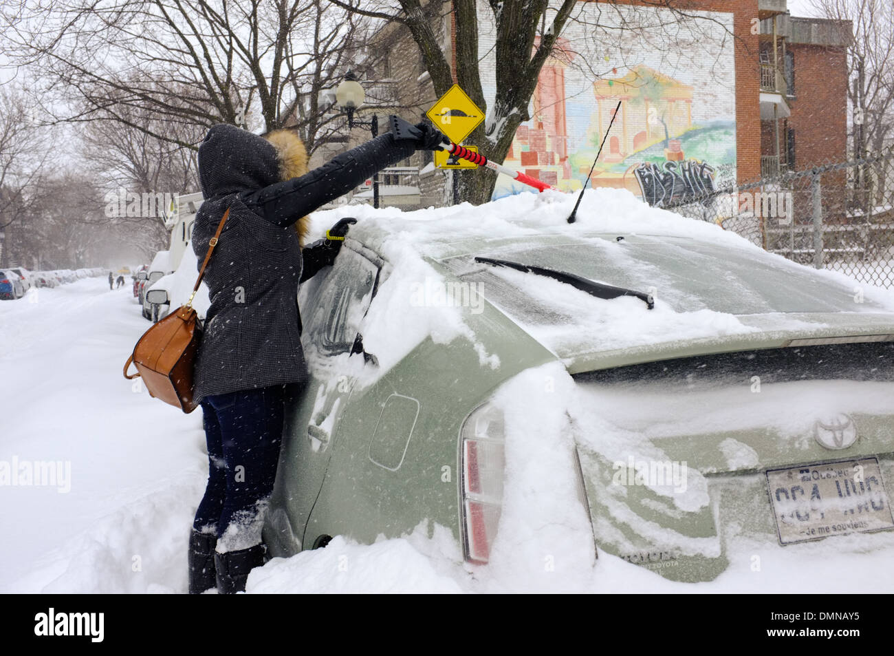 A woman clears off her car during a snowstorm that left her hybrid ...