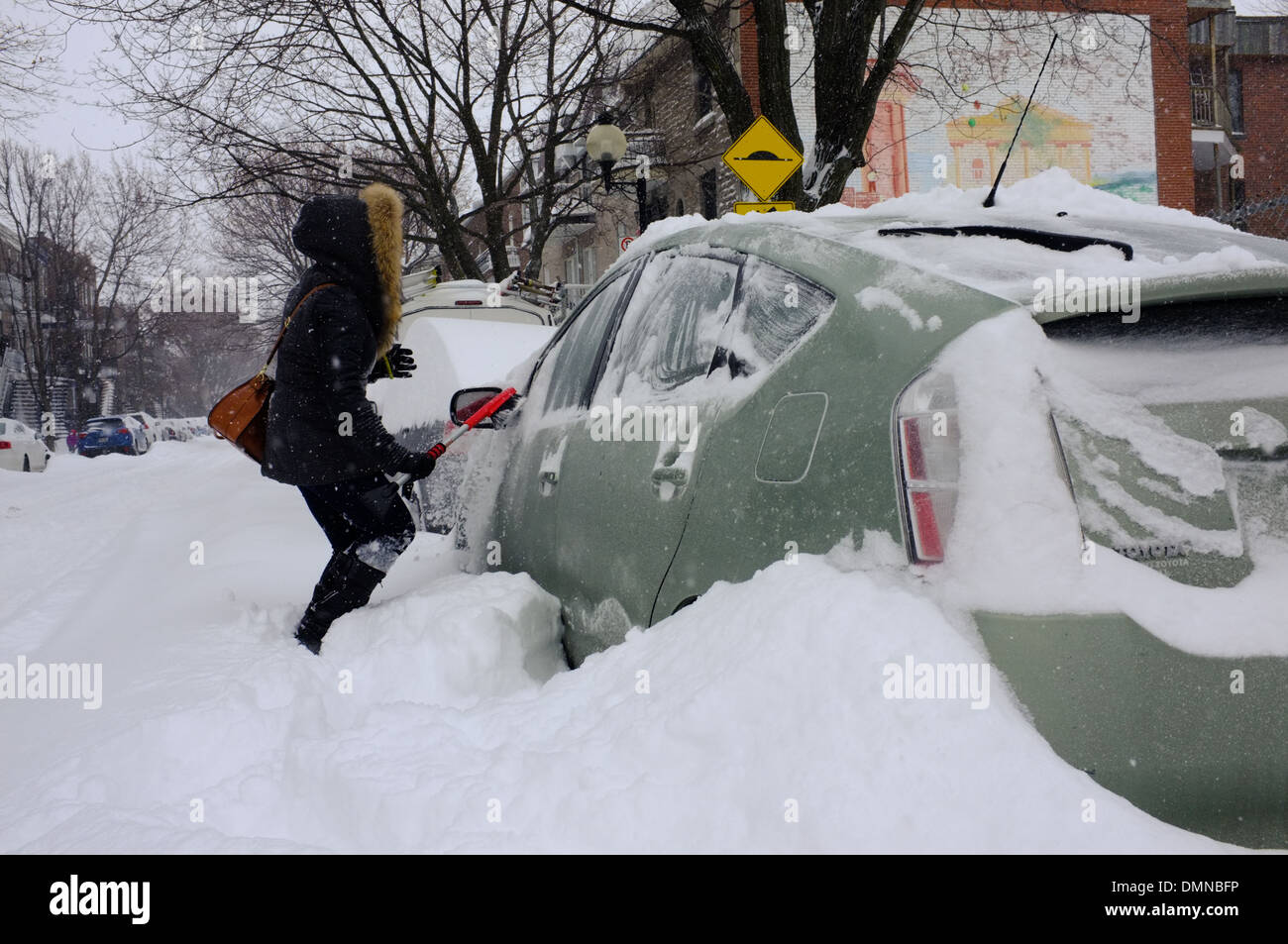 A woman clears off her car during a snowstorm that left her hybrid stuck in Montreal, Quebec ...