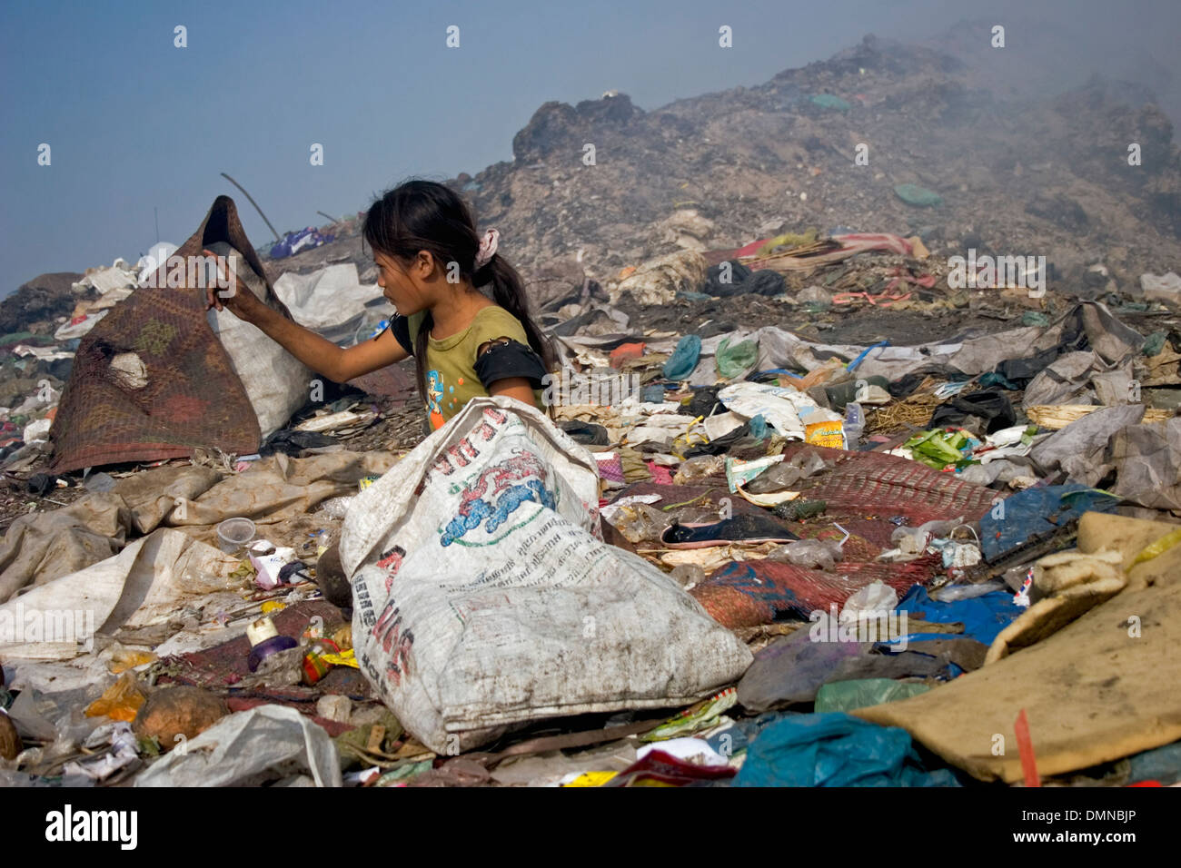 A young child laborer girl is collecting recyclable material at the ...