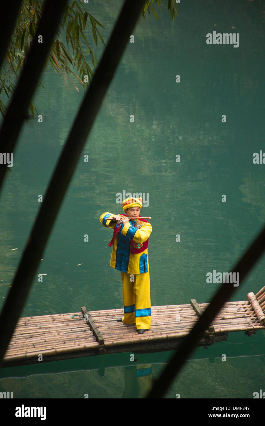 Tribal man playing flute on raft on Daning River China Stock Photo - Alamy