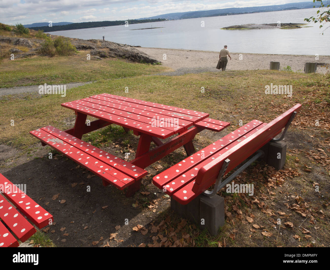 Red park benches decorated with white dots on a beach in the Oslo fjord ...