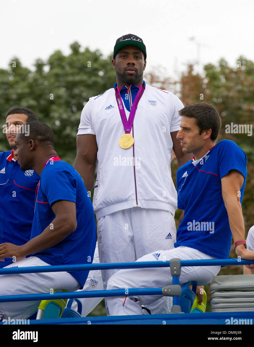 A French athlete celebrates on top of a double decker bus surrounded by ...