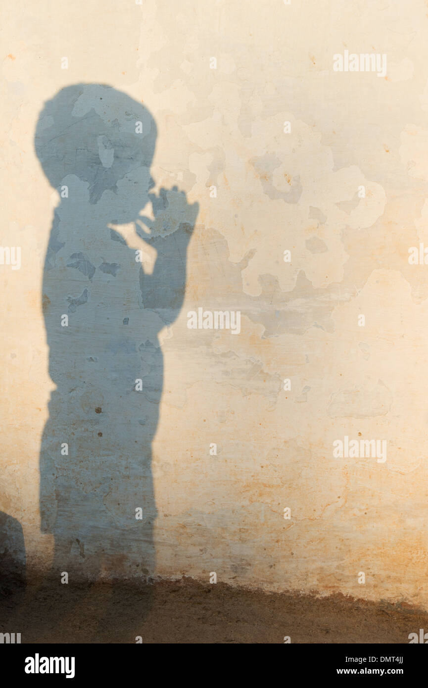 Young rural Indian village boys shadow on a sun lit wall with prayer ...
