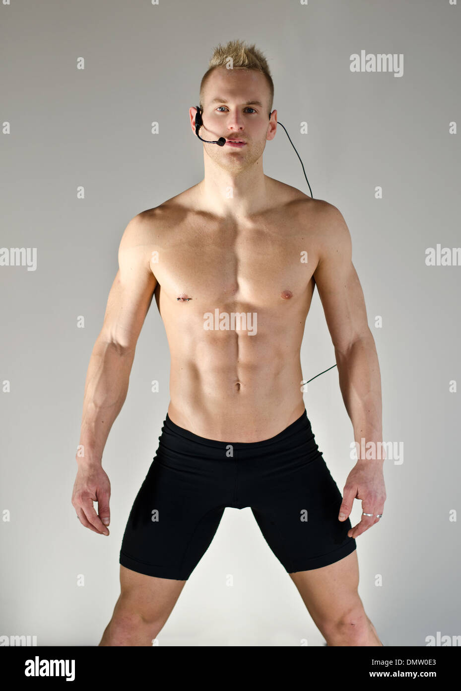 Young aerobics male coach shirtless standing on step teaching class ...