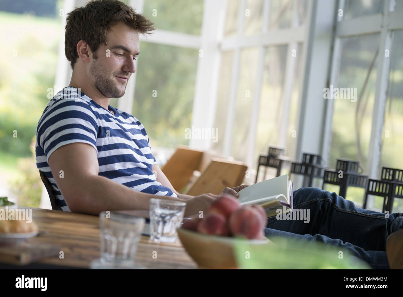 A man sitting at a table reading a book Stock Photo - Alamy