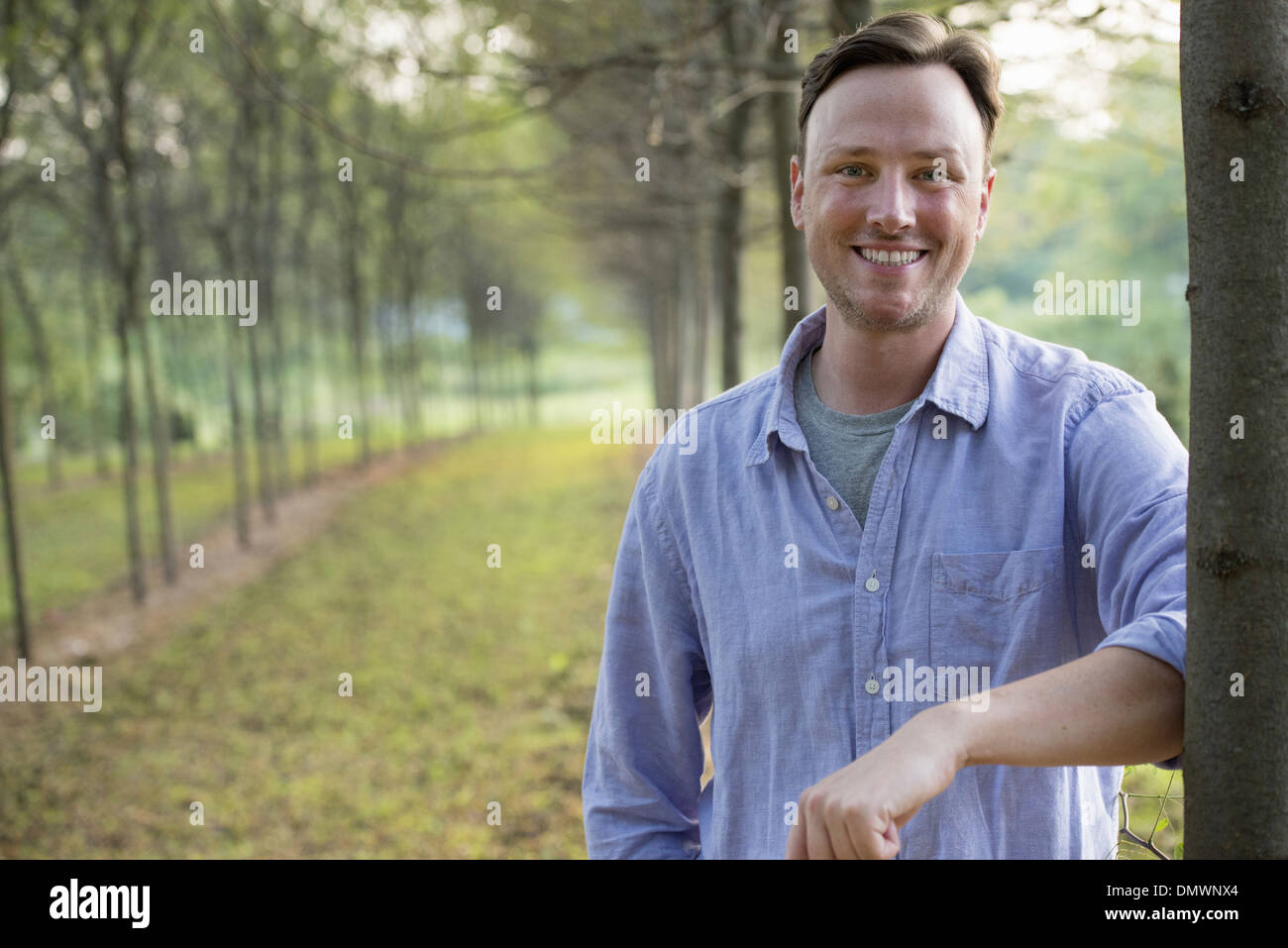 A man leaning against a tree looking at camera Stock Photo - Alamy