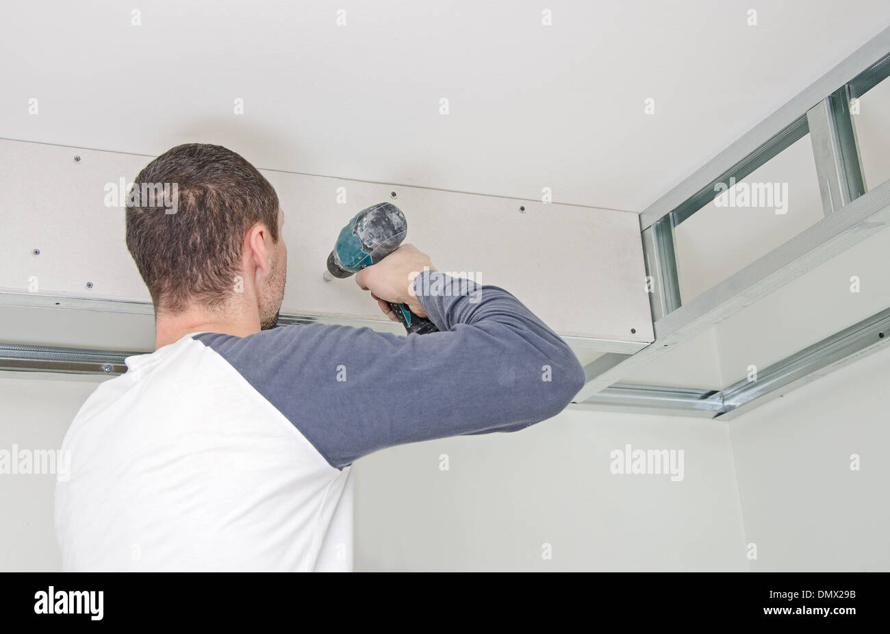 Builder mounting gypsum plasterboard frame on the wall Stock Photo - Alamy