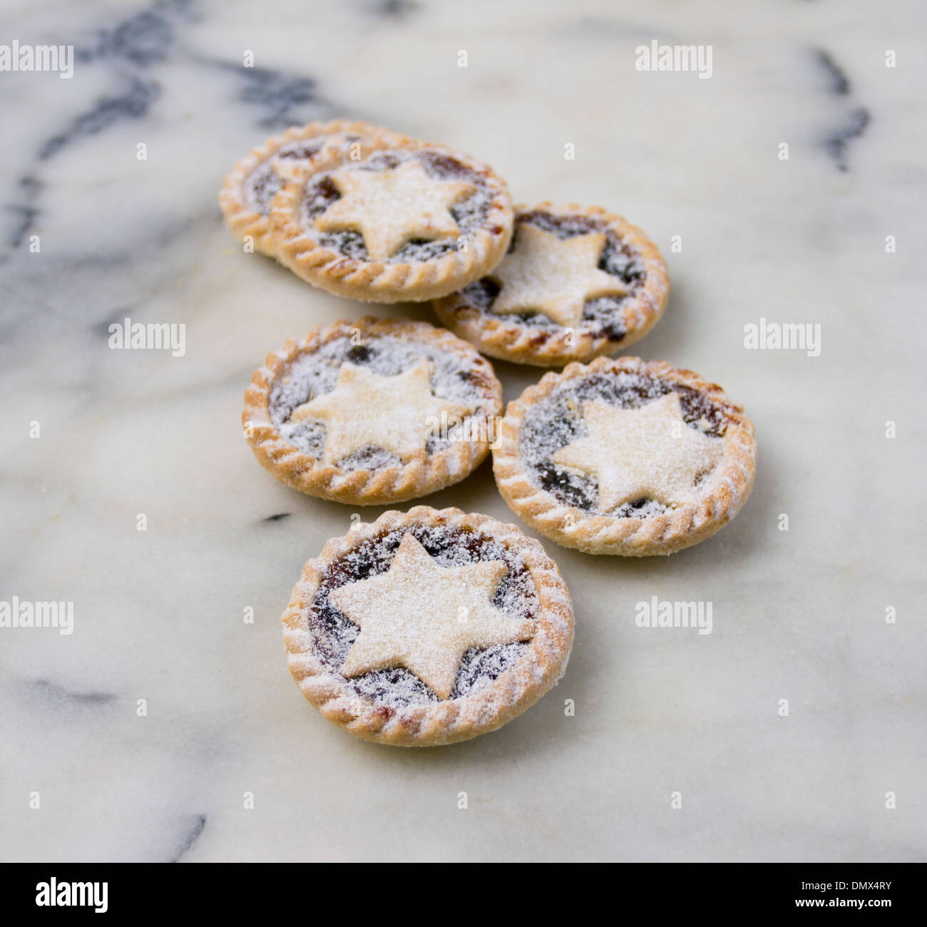 Six home made icing sugar dusted mince pies on grey marble surface ...