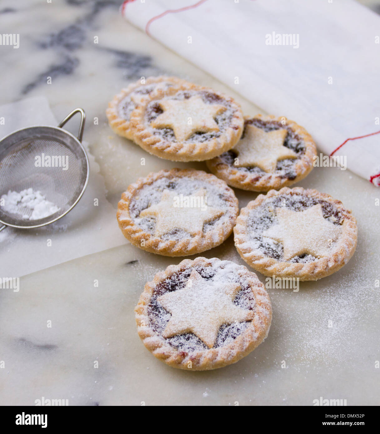 Home made icing sugar dusted mince pies on grey marble surface with ...