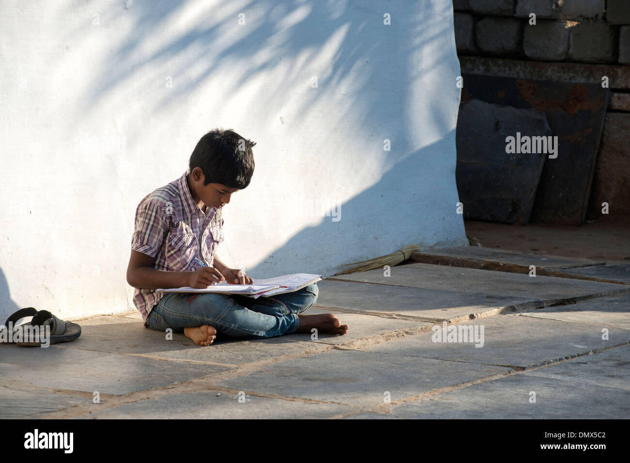 Young Indian boy doing school work outside his rural Indian village ...