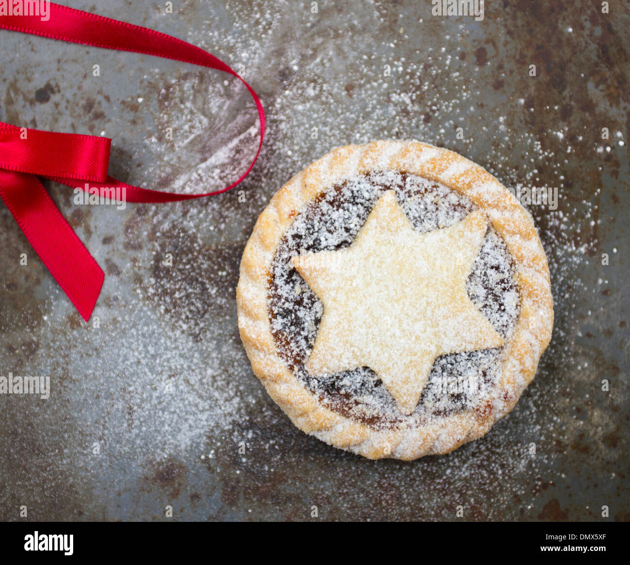 Home made icing sugar dusted mince pie on a rustic grey metal surface ...