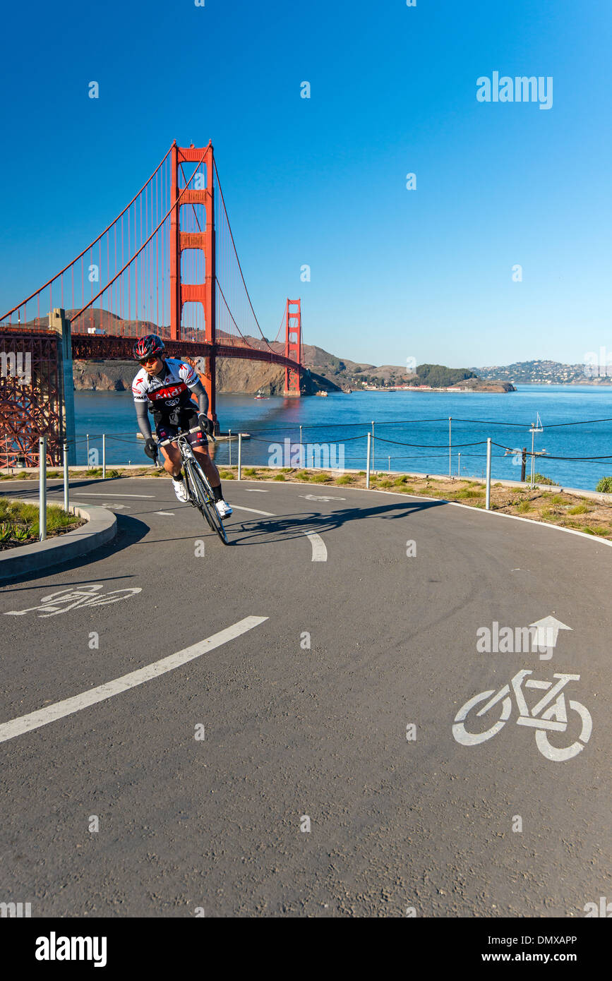 Cyclist riding his mountain bike on a bike lane with Golden gate ...