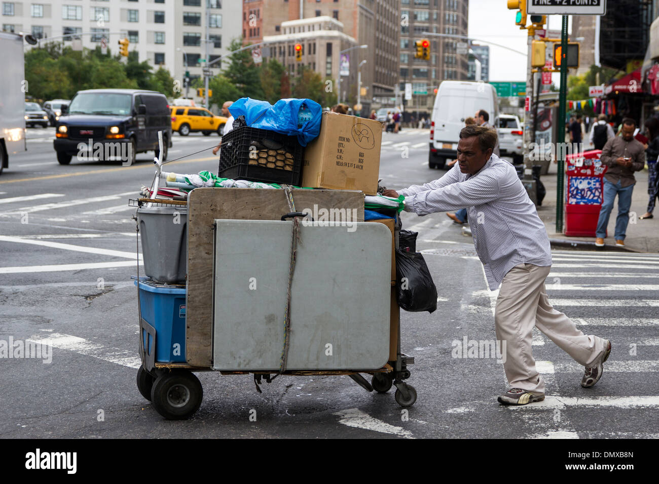 Man pushing rubbish in the street Stock Photo - Alamy