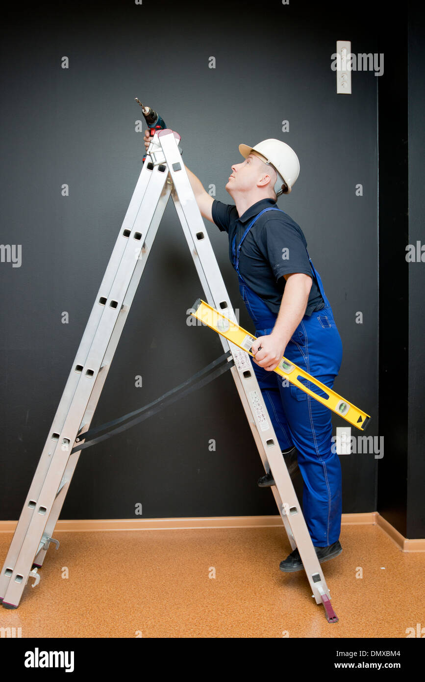 worker with tools, stands on a ladder Stock Photo - Alamy