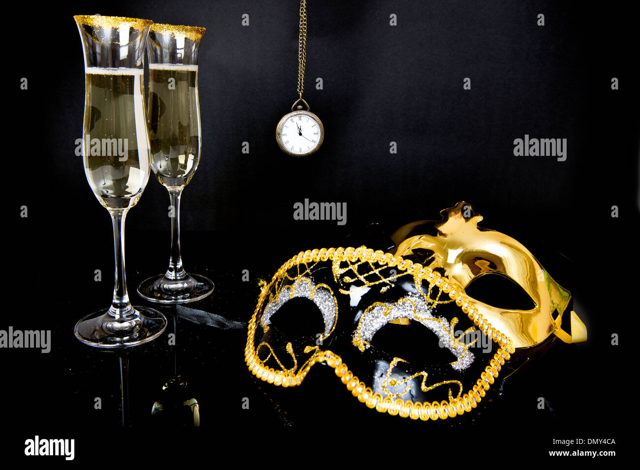 two glasses of champagne, two Venetian masks and watch on a black ...