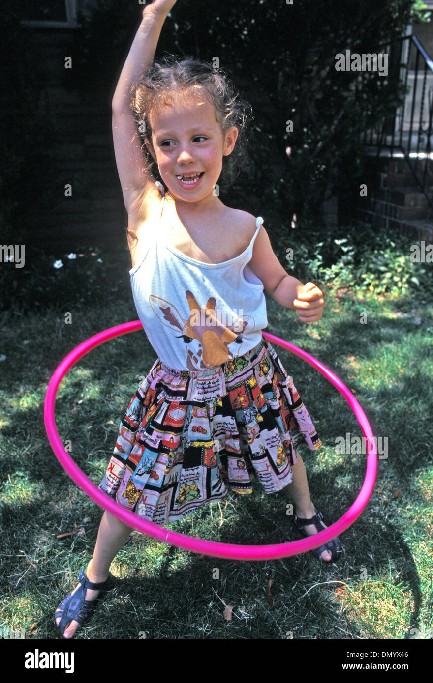 Young girl doing the "hoola" with her hoola hoop in her yard in ...