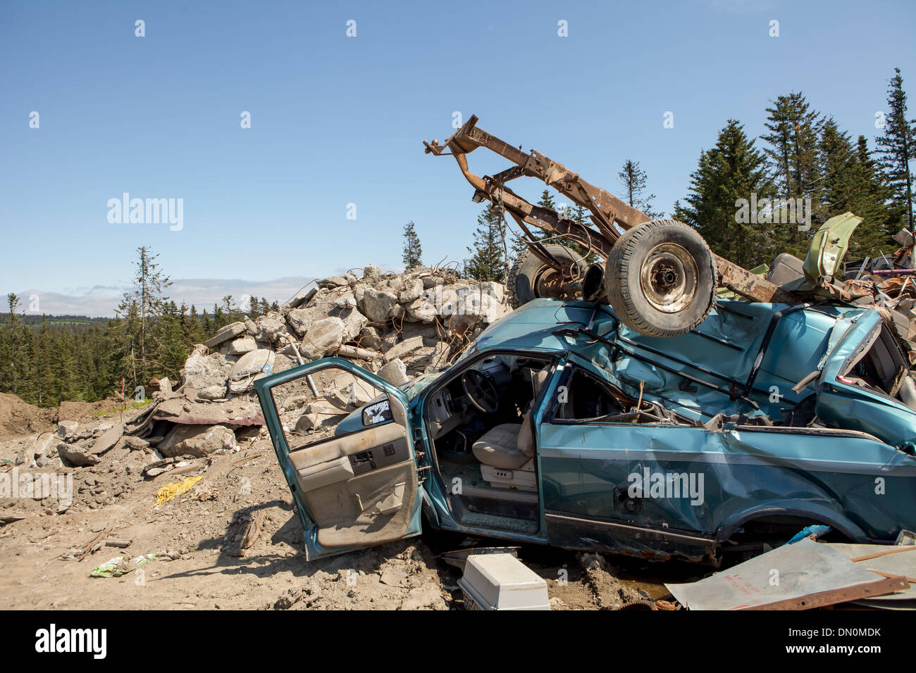 Smashed car after an accident in a dump with other trash on a sunny day ...