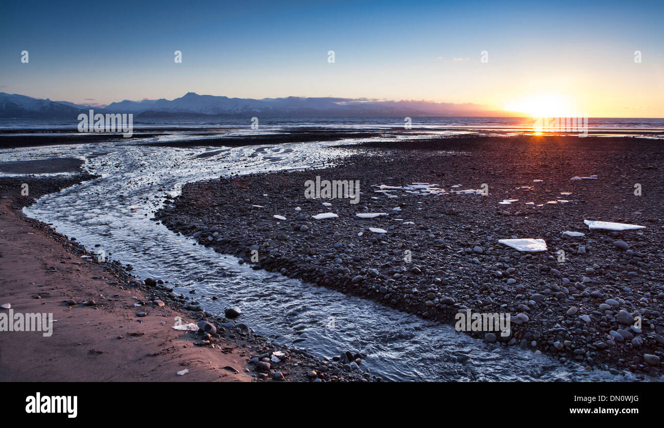 Water flowing to the sea on an Alaskan beach at sunset with some ice ...