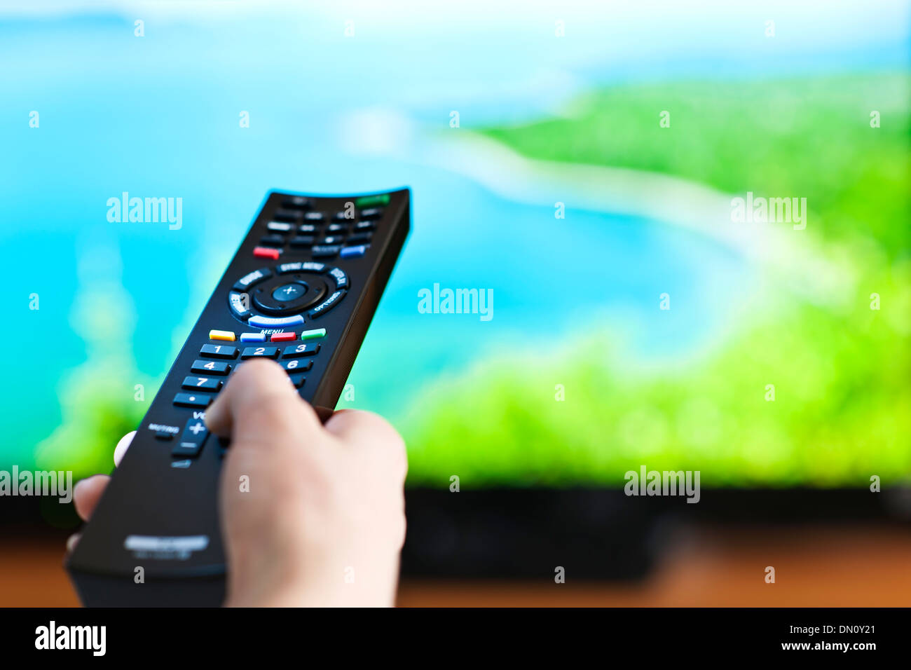 Hand holding television remote control pressing buttons Stock Photo - Alamy