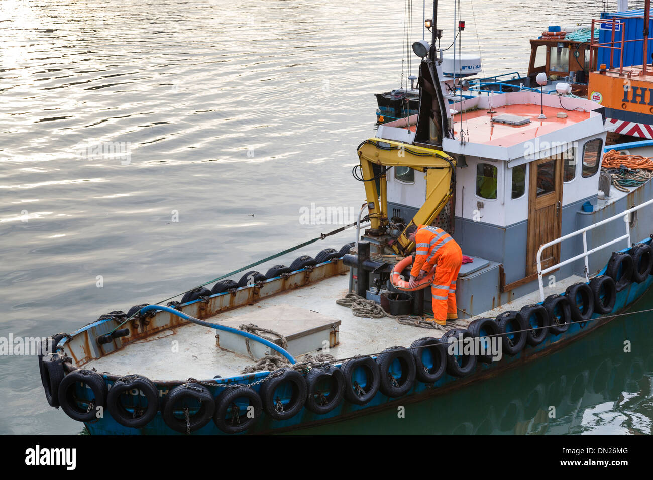 Workman with a life buoy on a tugboat Stock Photo - Alamy