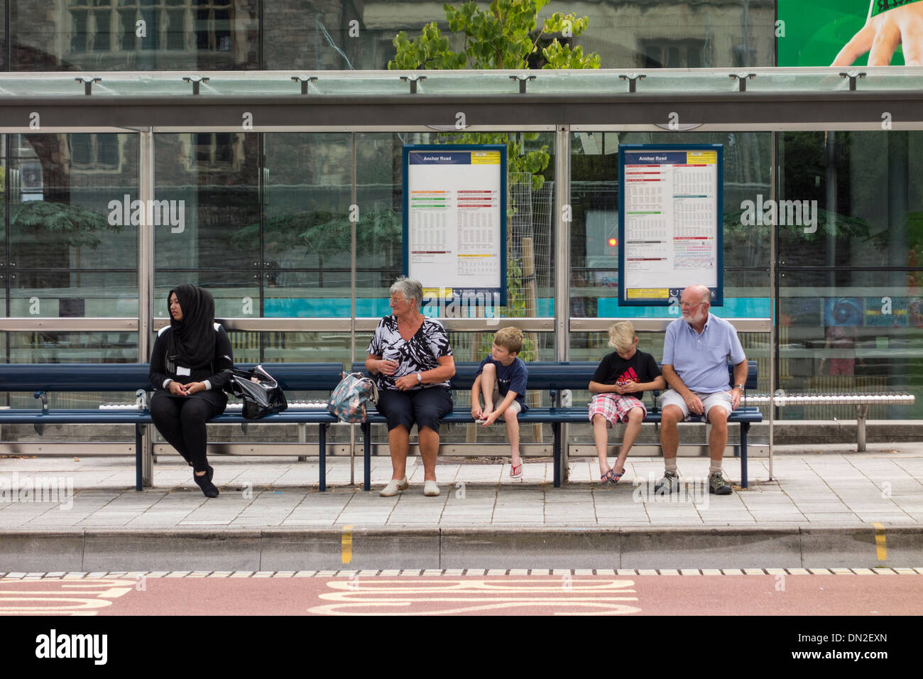 People sitting and waiting for bus at bus stop shelter, Bristol, UK ...