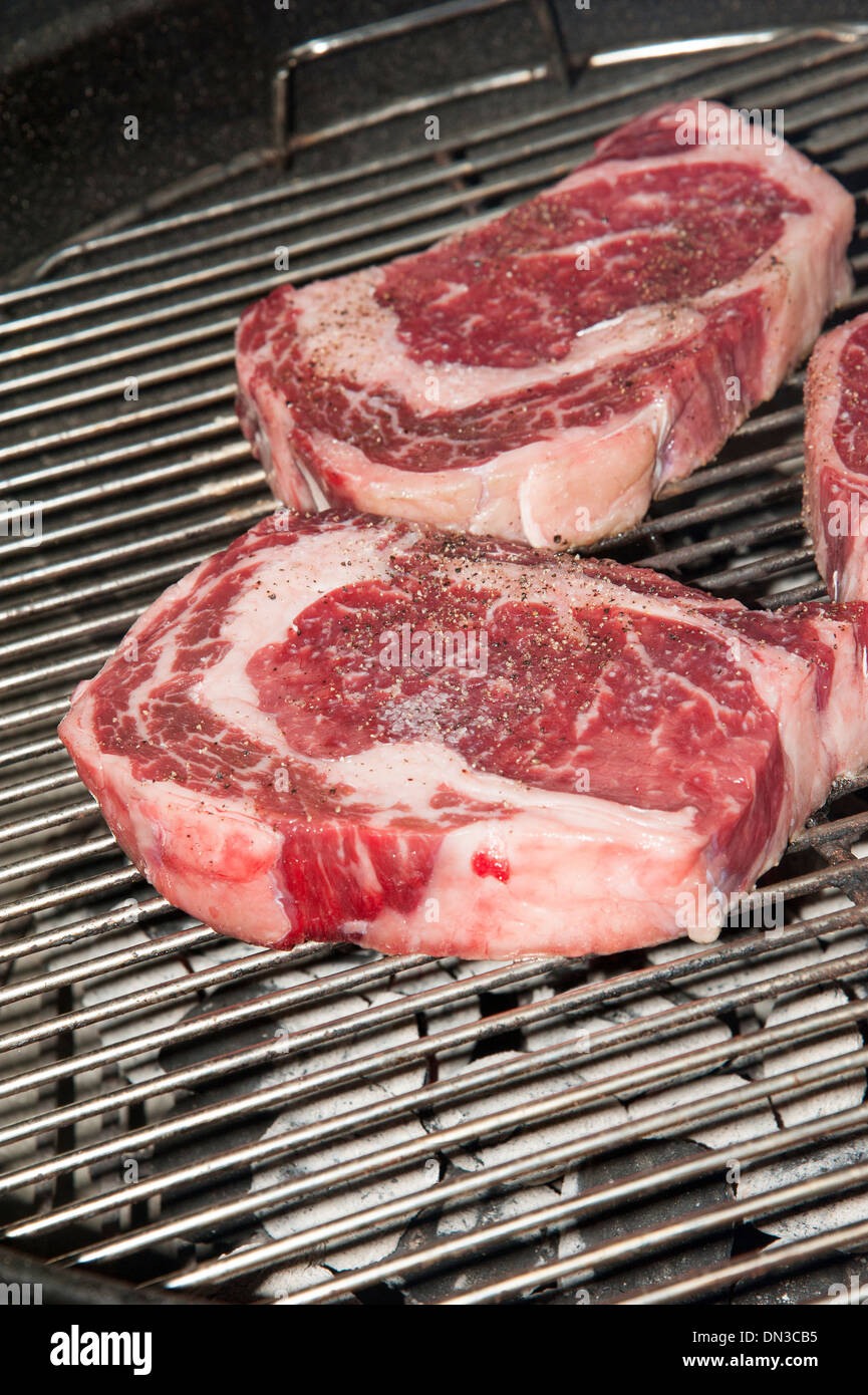 American Ribeye steaks cooking over coals on a barbecue Stock Photo - Alamy
