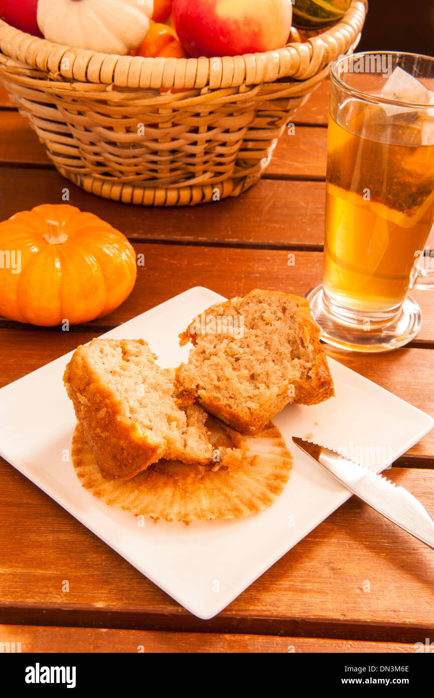 Muffin sliced in half on a plate with a cup of tea and pumpkins Stock ...