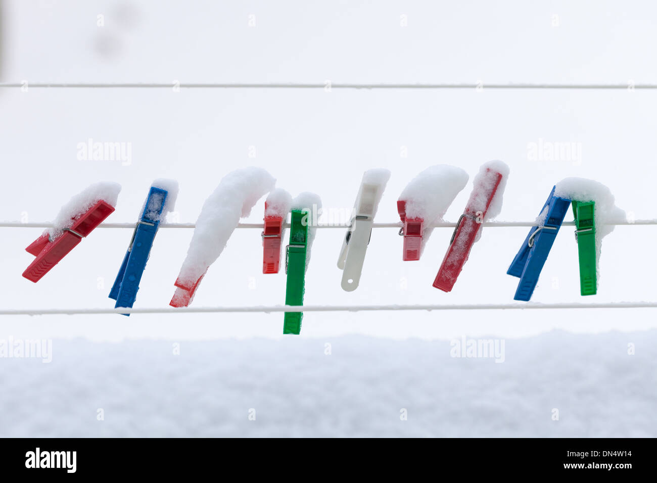 Colorful clips for washing laundry covered with snow on strip rope ...