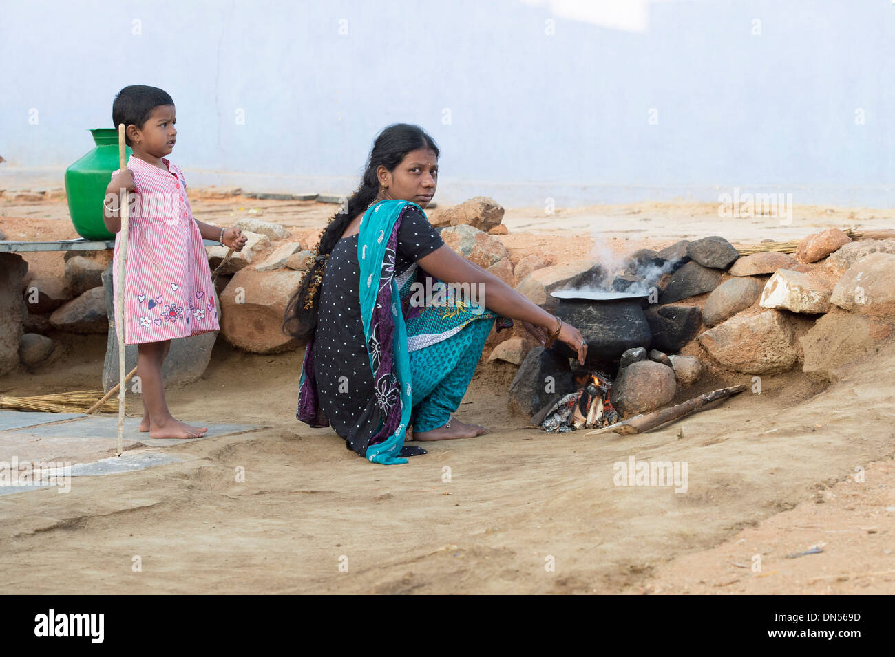 Indian woman and child keeping warm by an open fire in a rural Indian ...