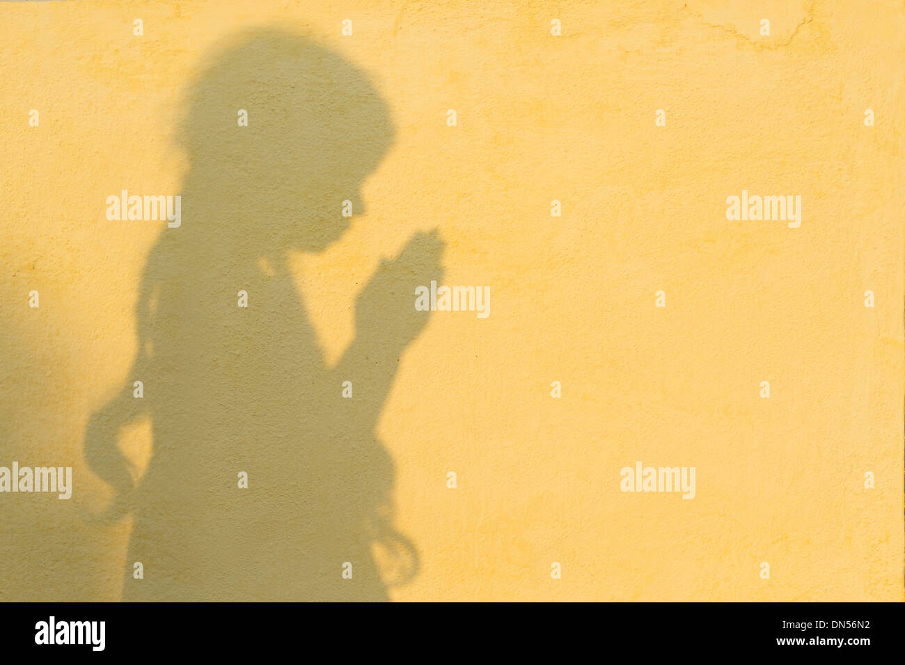 Young rural Indian village girls shadow on a sun lit wall with prayer ...