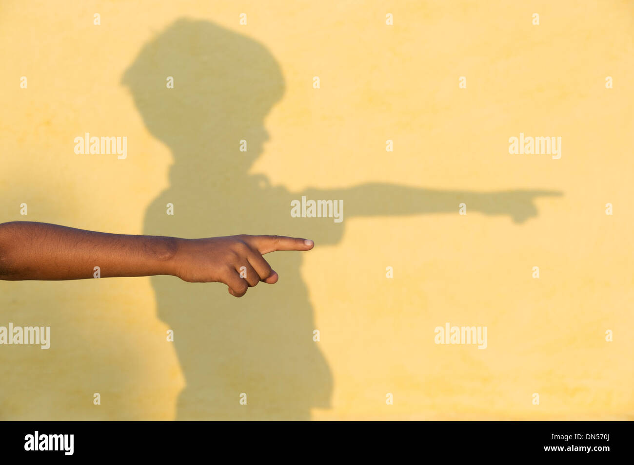 Young rural Indian village boys pointing hand with shadow on a sun lit ...