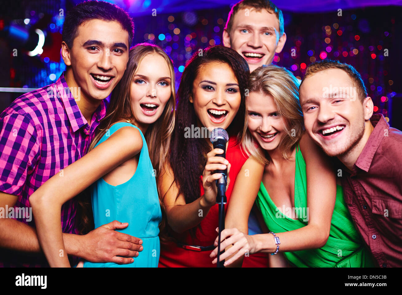 Portrait of happy girls and guys singing in microphone in the karaoke ...