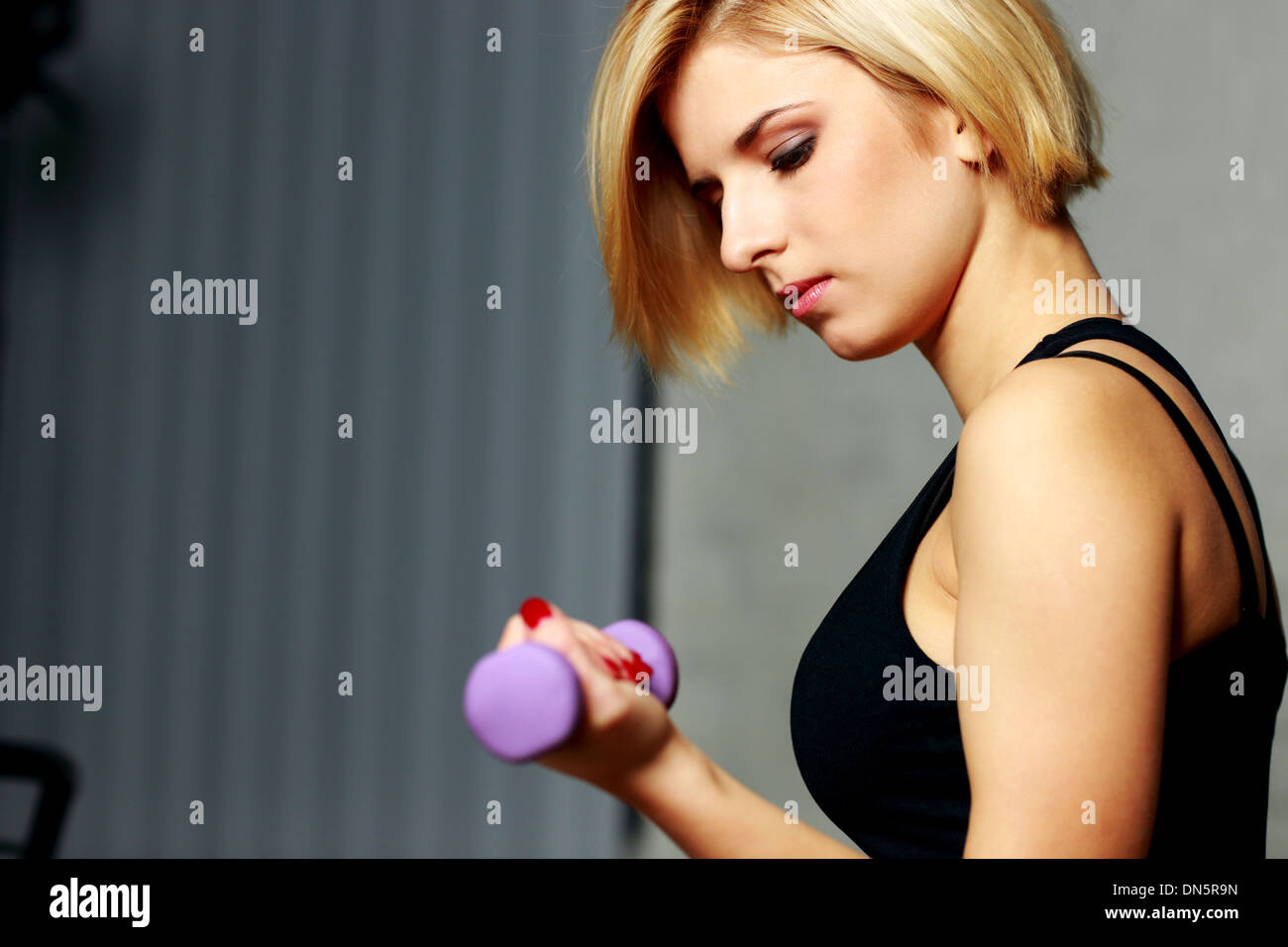 Portrait of a young fit woman doing workout with dumbbell Stock Photo ...