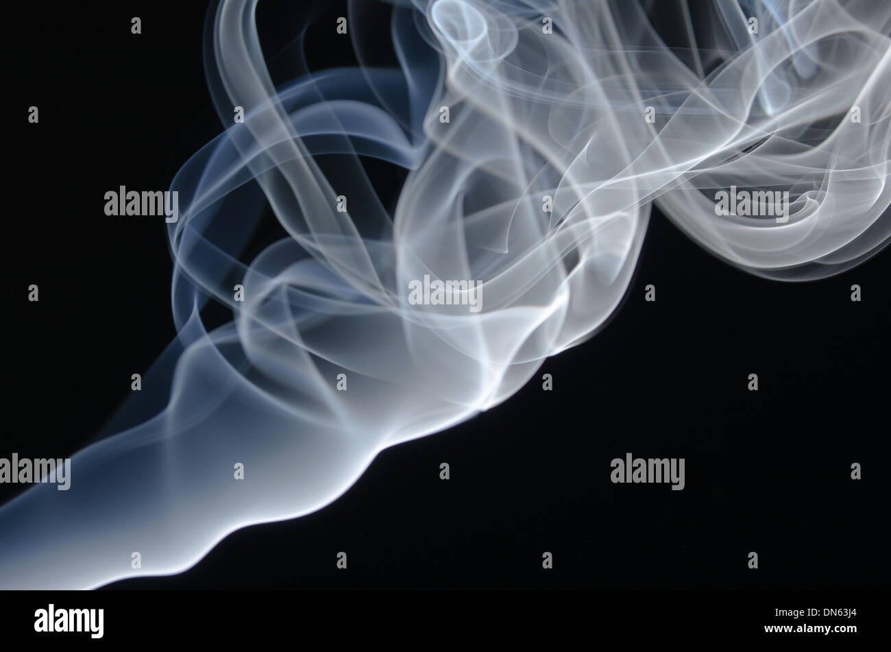 Wavy smoke trail against black background creating patterns calmness ...