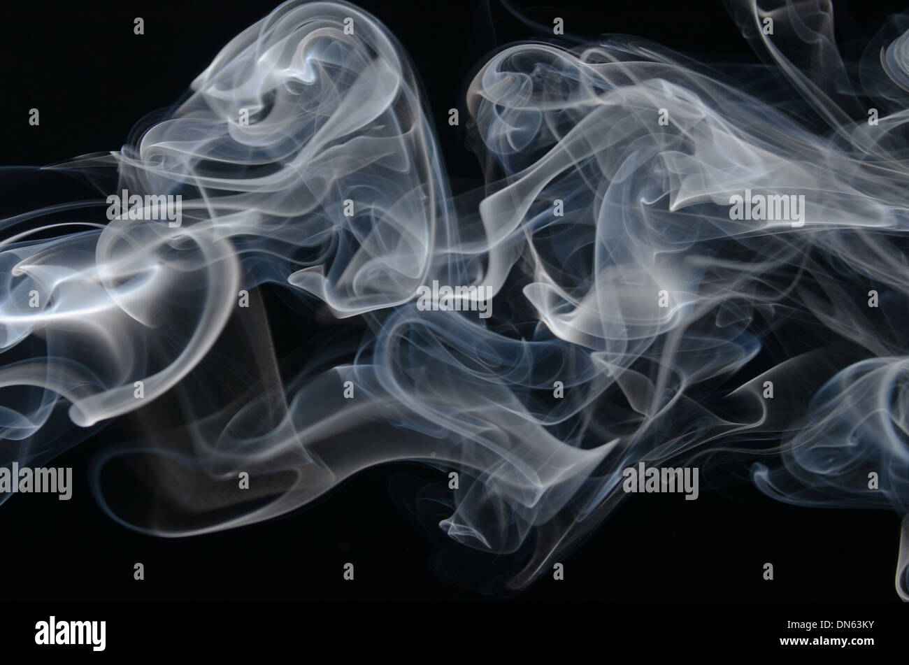 Wavy smoke trail against black background creating patterns calmness ...