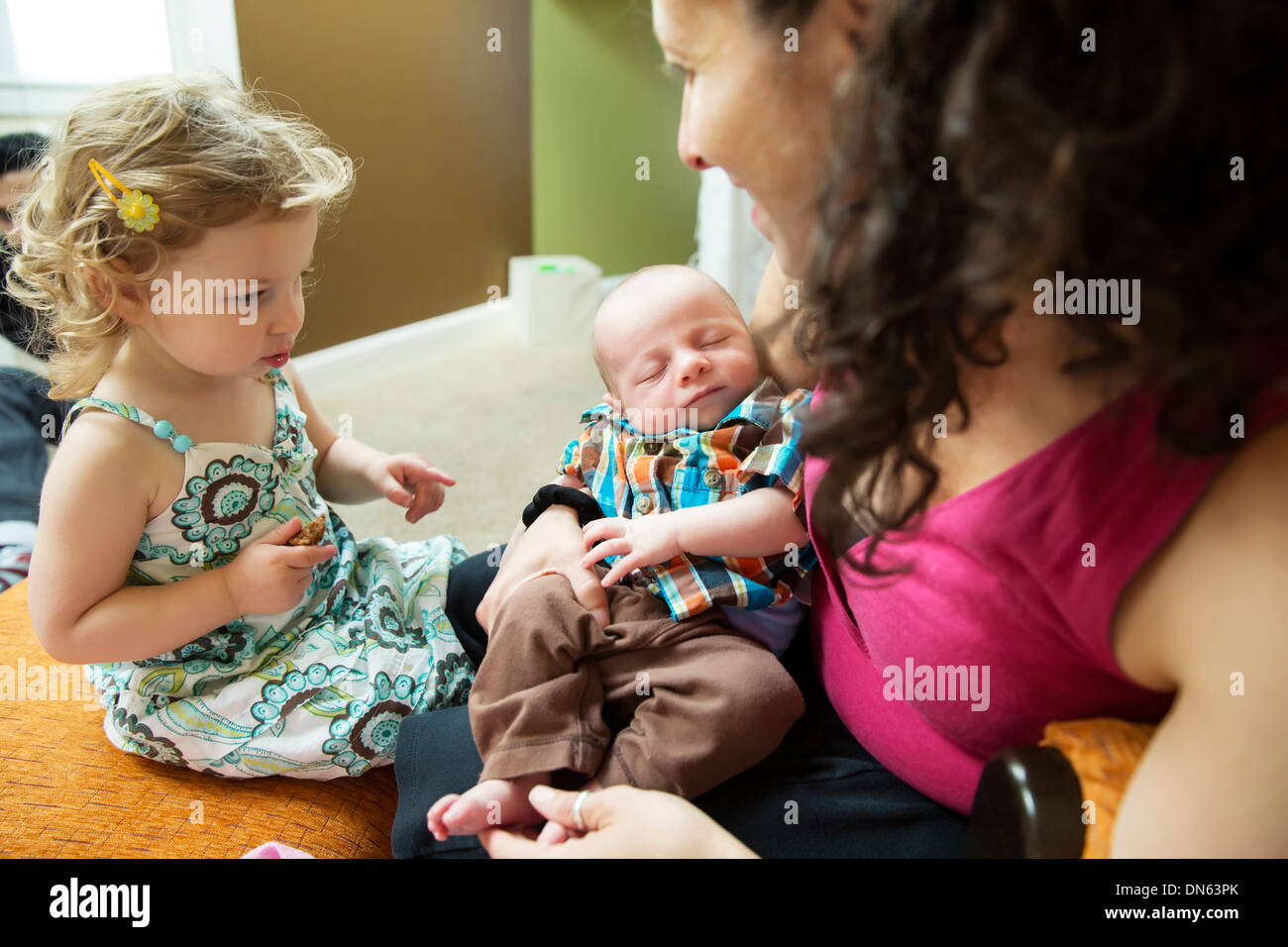 Caucasian girl watching mother hold newborn boy Stock Photo - Alamy