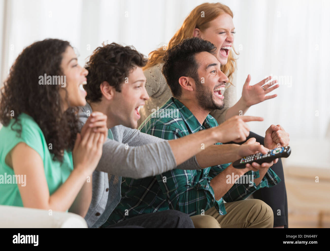 Friends watching television together on sofa Stock Photo - Alamy