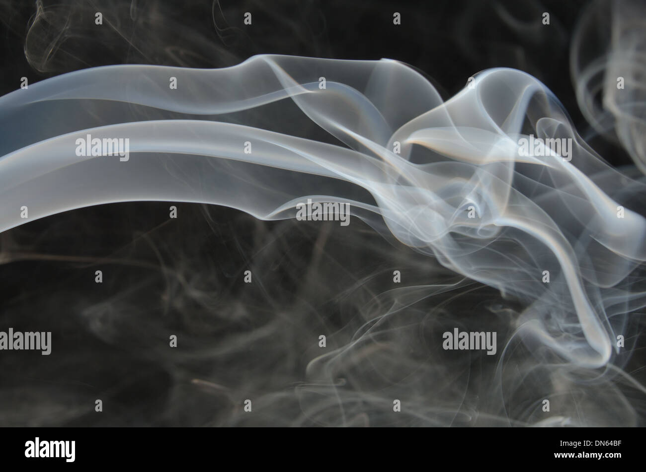 Wavy smoke trail against black background creating patterns calmness ...