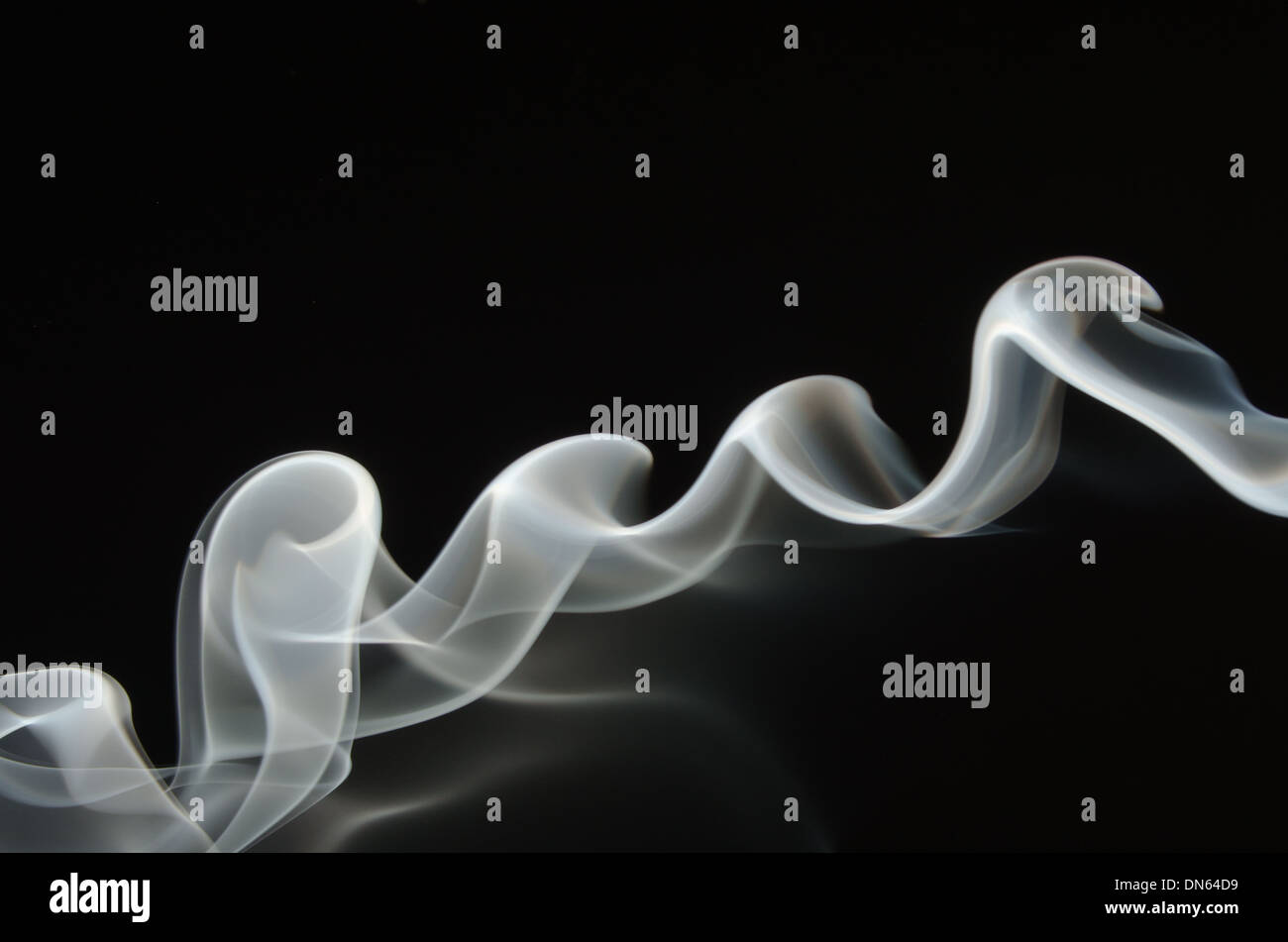 Wavy smoke trail against black background creating patterns calmness ...