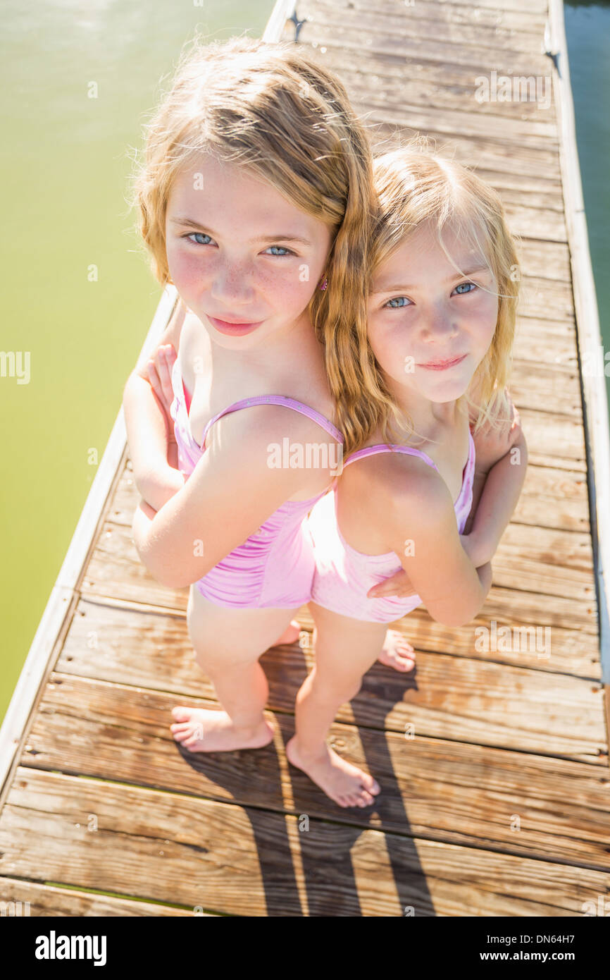Caucasian girls standing back to back on dock Stock Photo - Alamy