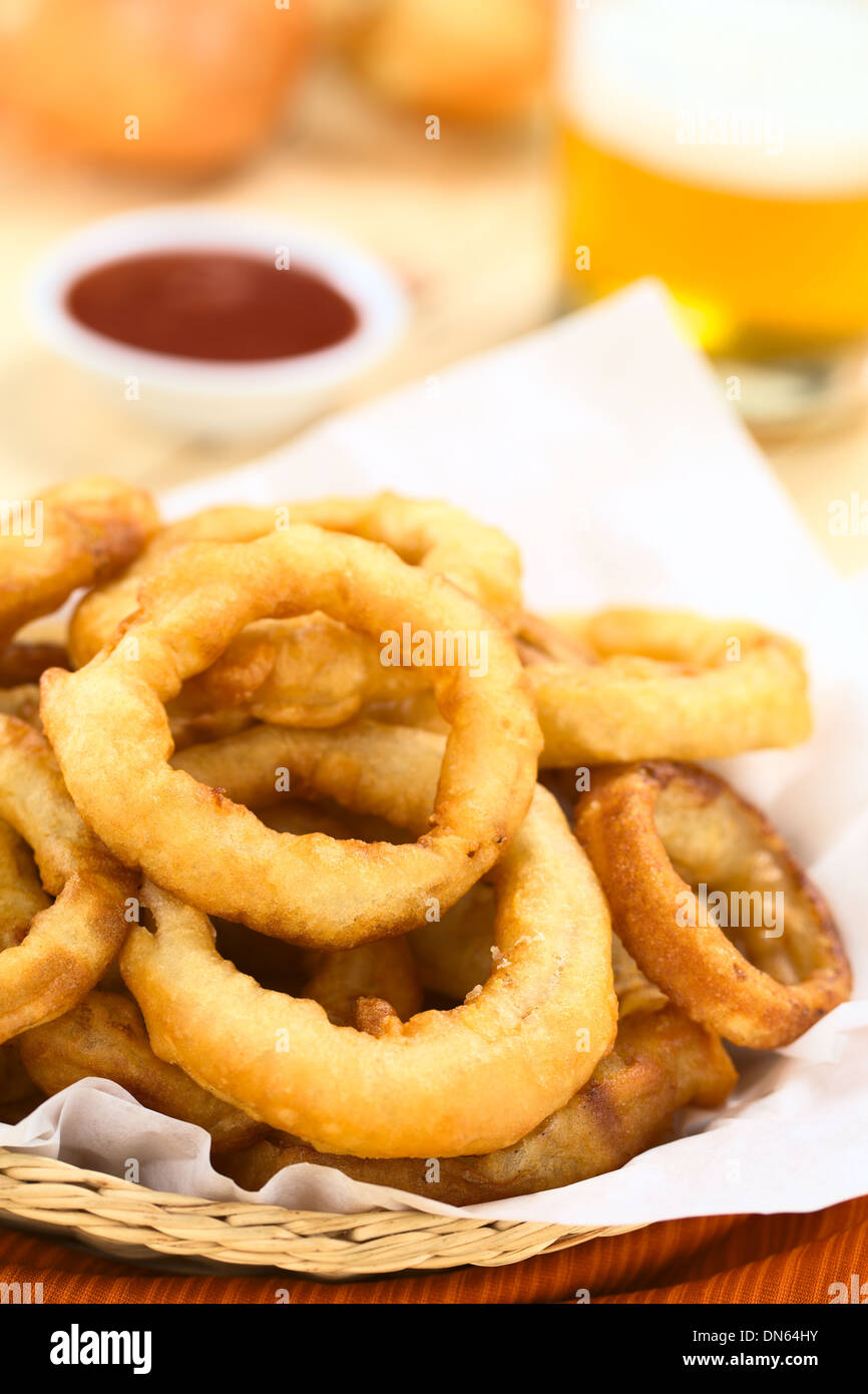 Freshly prepared homemade beer-battered onion rings in a basket with ...