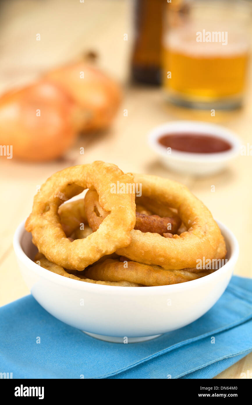 Freshly prepared homemade beer-battered onion rings in a bowl with beer ...