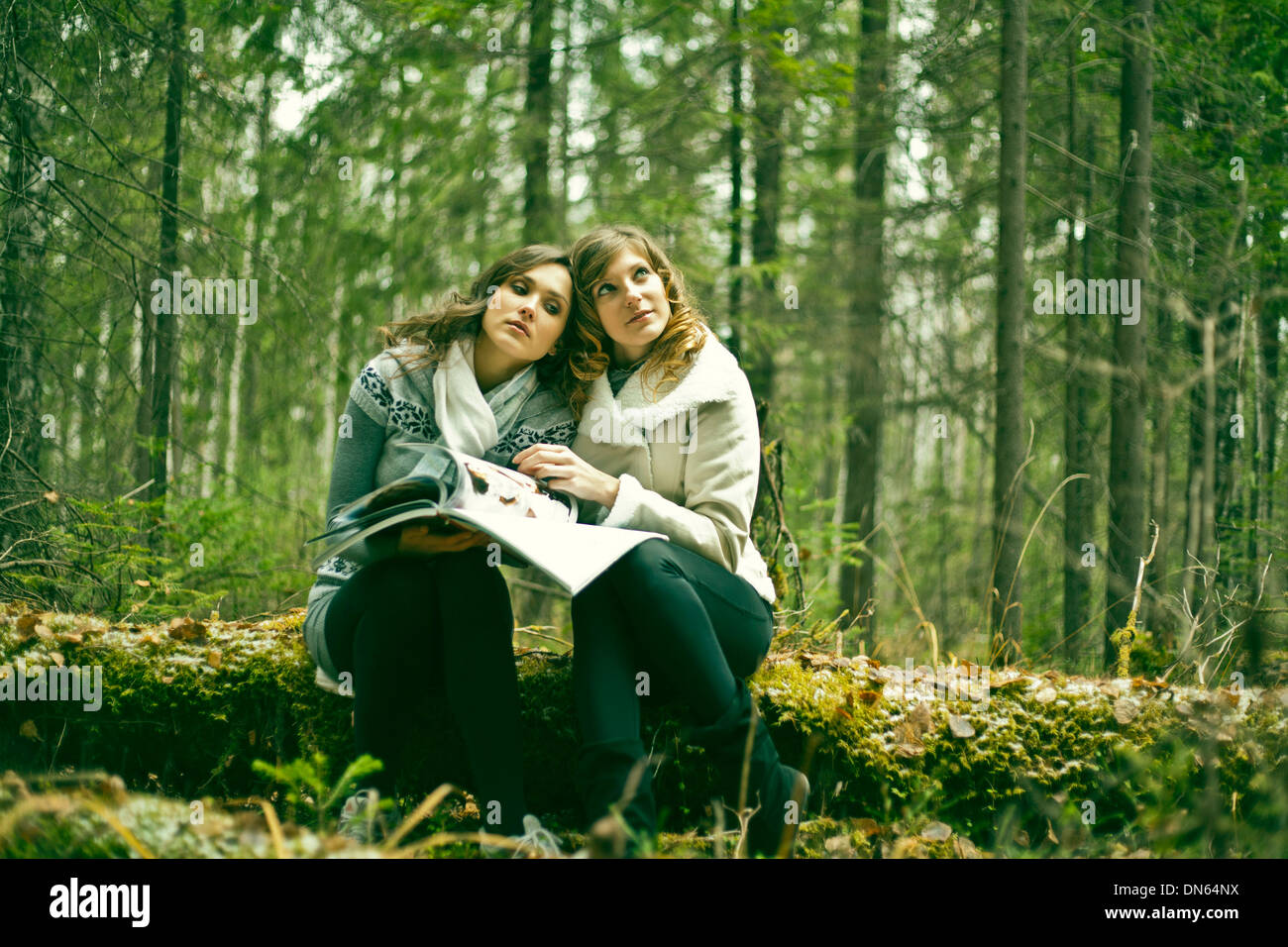 Two young women reading magazine sitting hi-res stock photography and ...