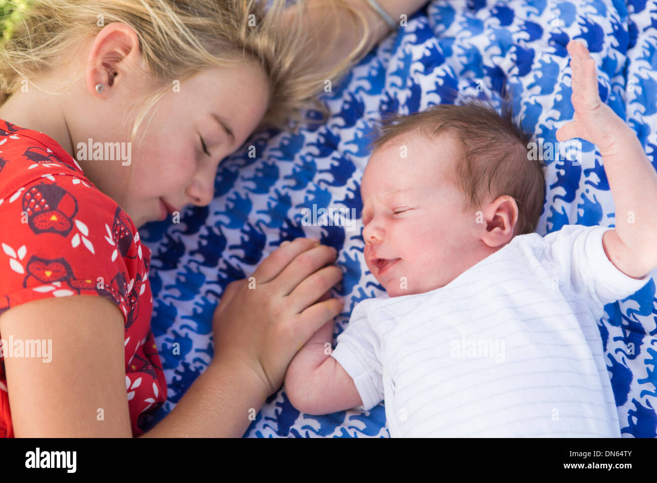 Caucasian girl laying with newborn baby brother Stock Photo - Alamy