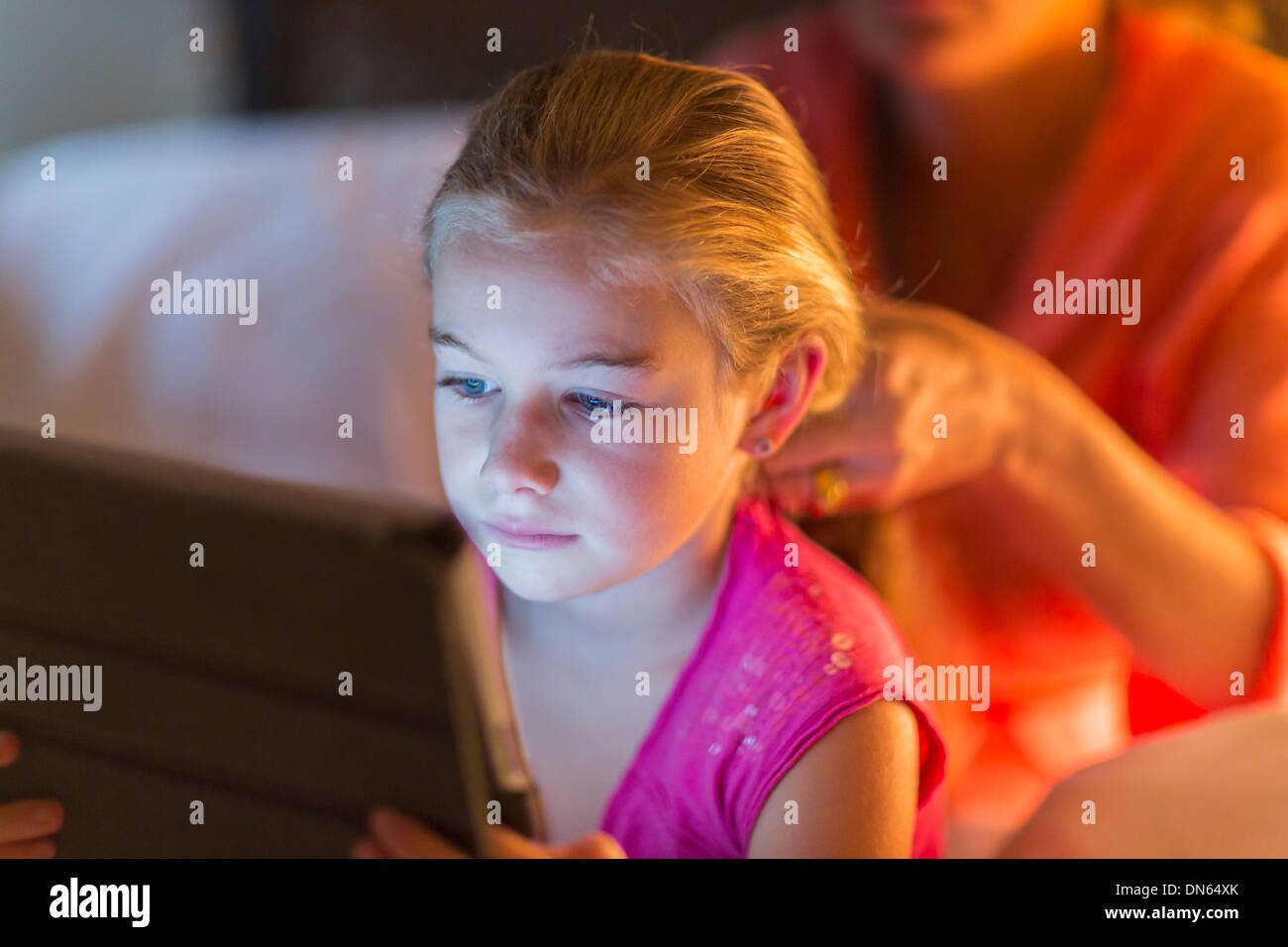 Caucasian girl using digital tablet as mother braids hair Stock Photo ...