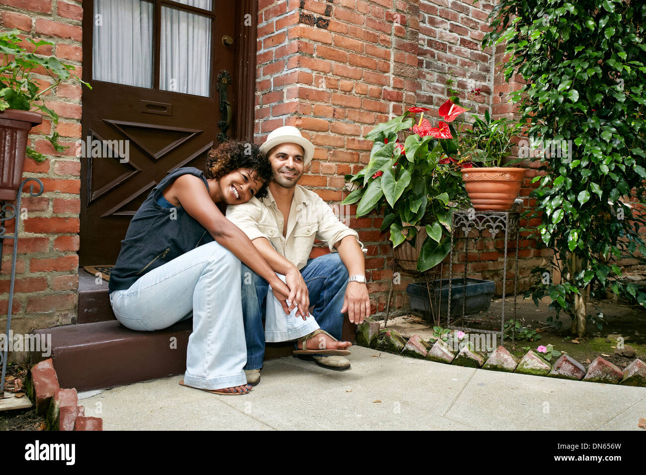 Couple smiling together on front stoop Stock Photo - Alamy