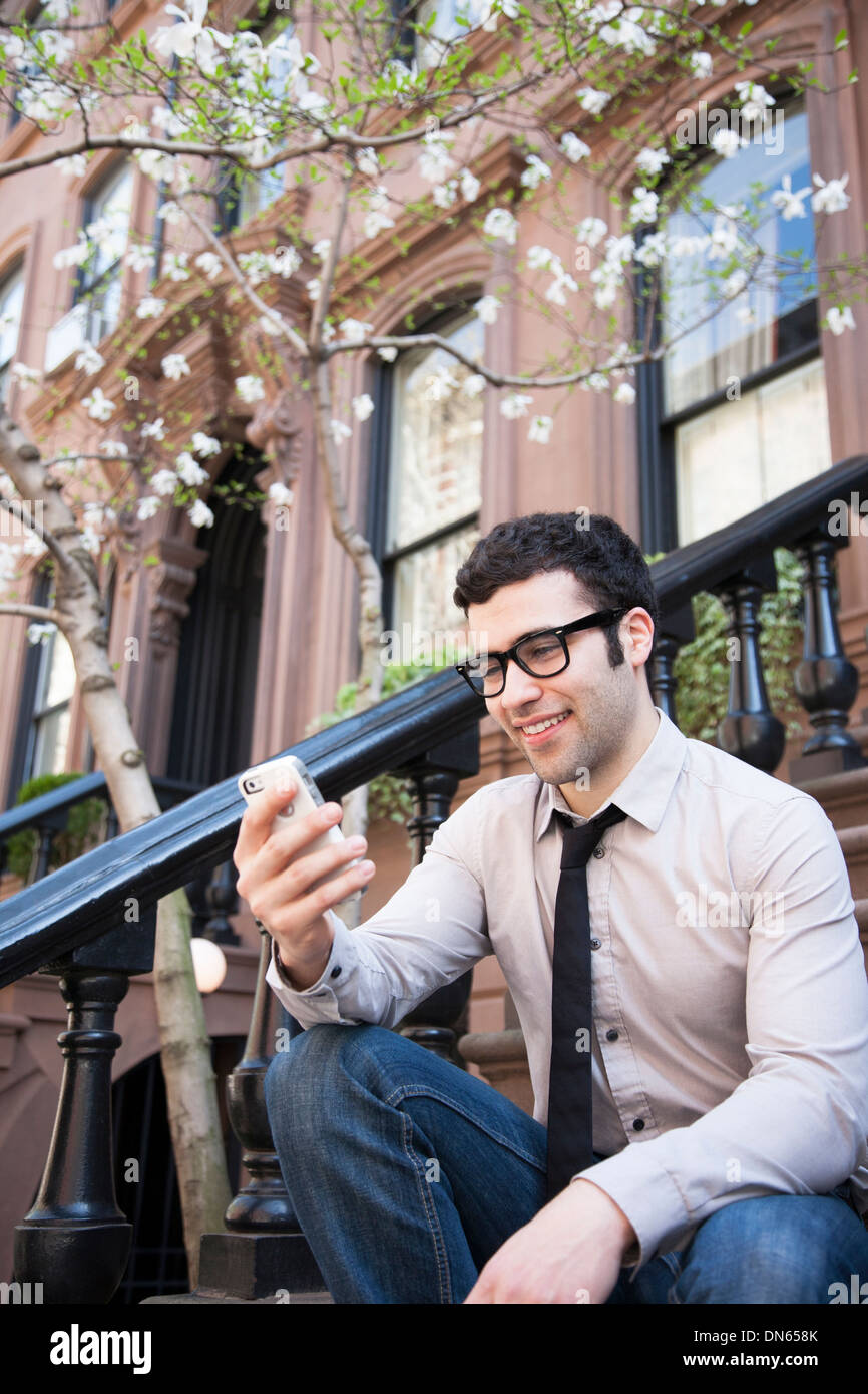 Hispanic businessman using cell phone on front steps Stock Photo - Alamy