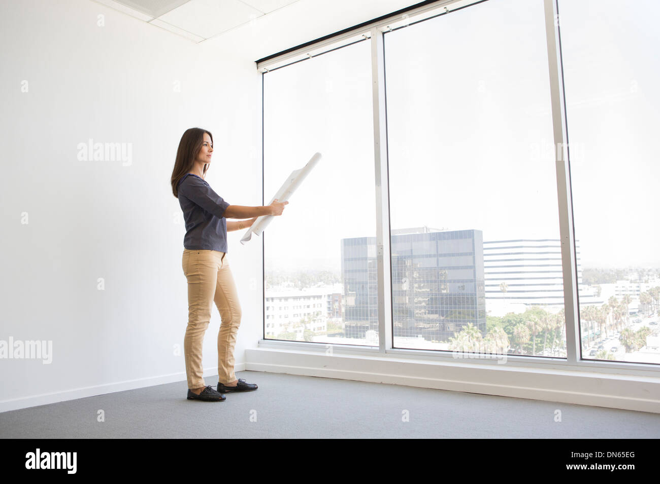 Woman reading blueprints in empty office Stock Photo - Alamy