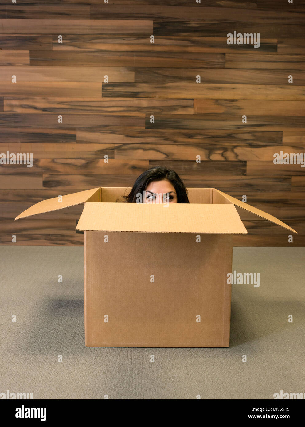 Mixed race woman hiding in cardboard box Stock Photo - Alamy
