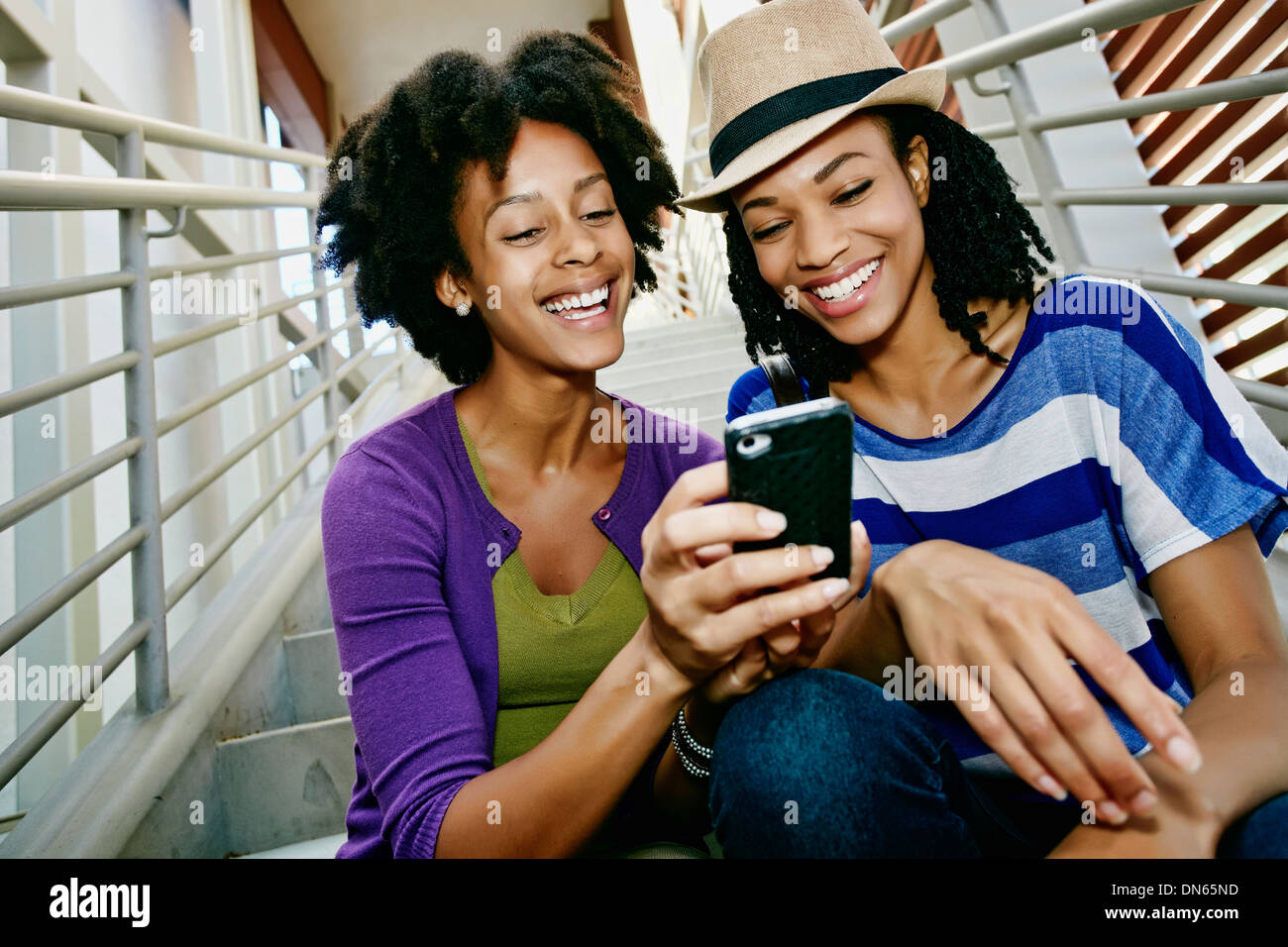 Women using cell phone together on steps Stock Photo - Alamy